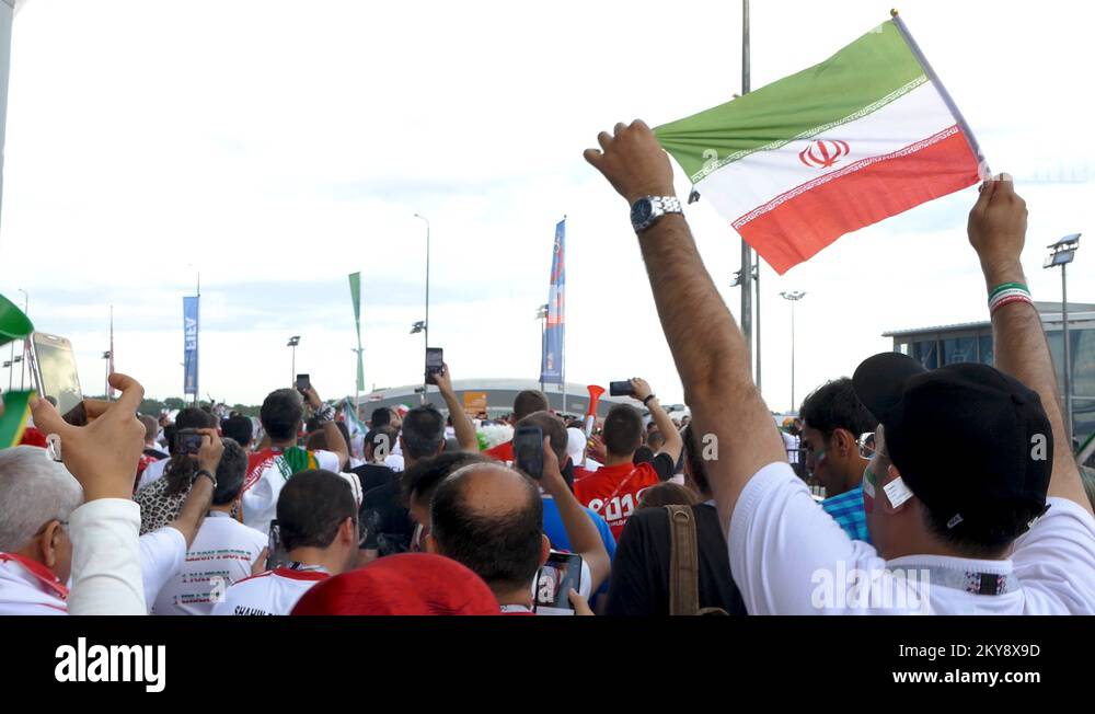 Tracking shot following Iranian crowd in street waving flag chanting ...
