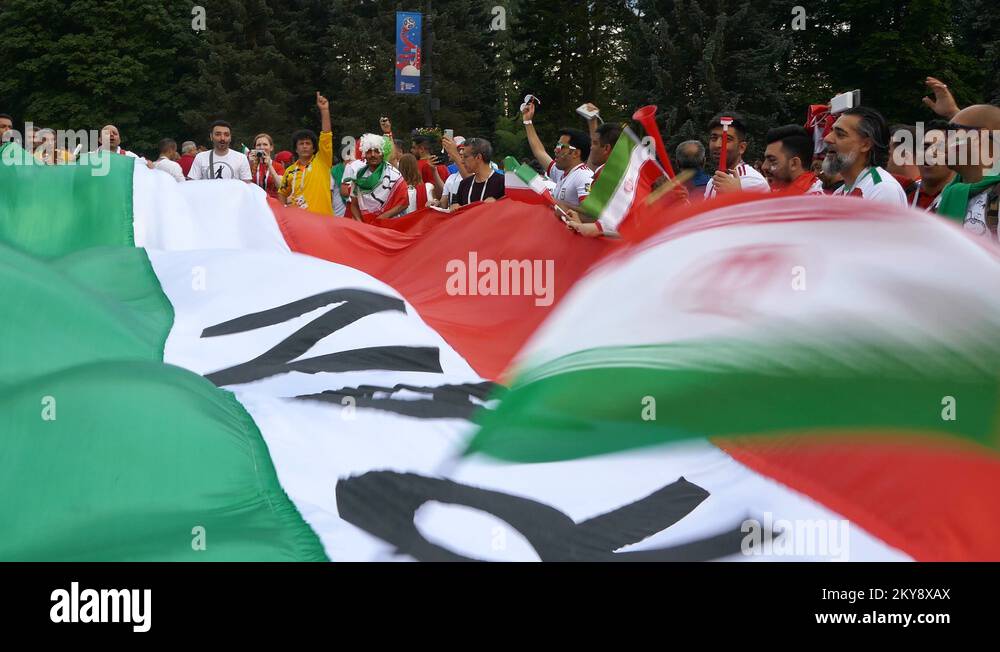 Iranian crowd of fans in street waving big giant flag singing ...