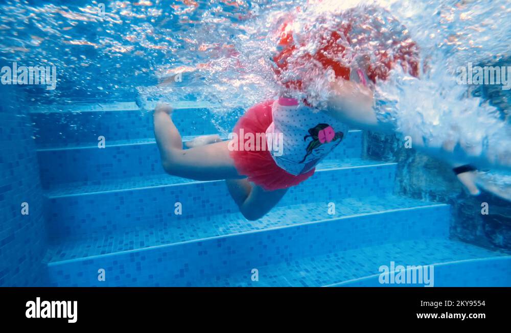 Underwater shot of a cute little girl learning how to swim in a pool ...