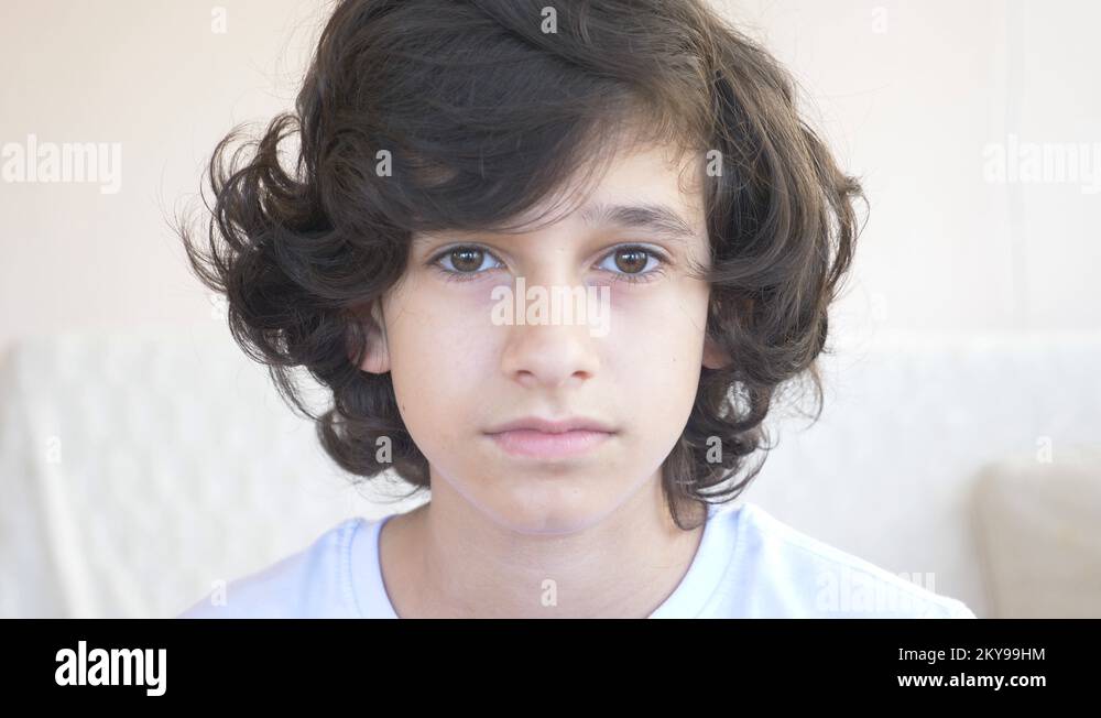 cute curly-haired boy teen looking into camera and making funny face ...