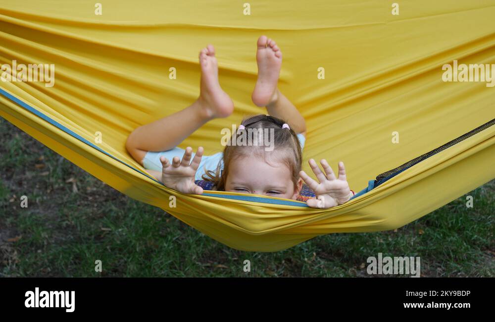 8 Girl child funny amuse enjoy lying in yellow hammock wagging ...