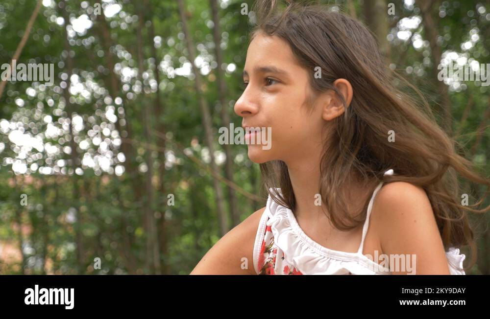 Cute little girl brunette, eating fruit and talking. Nature background ...