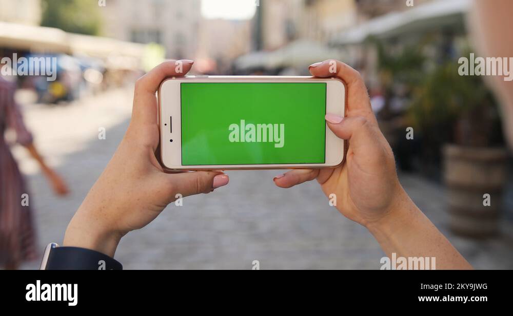 woman hand holding mobile smart phone with horizontally green screen ...