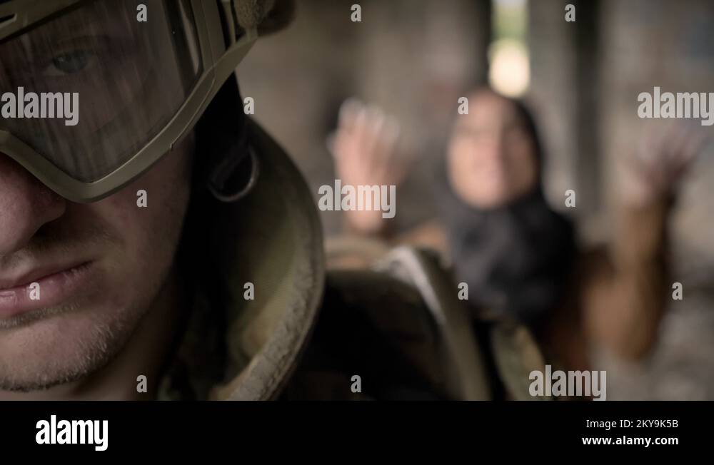 Armed soldier looking at camera when muslim woman in hijab screaming ...