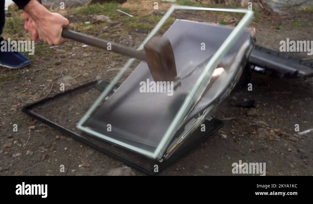 Man swings sledge hammer into printer, compuer and monitor on nature ...