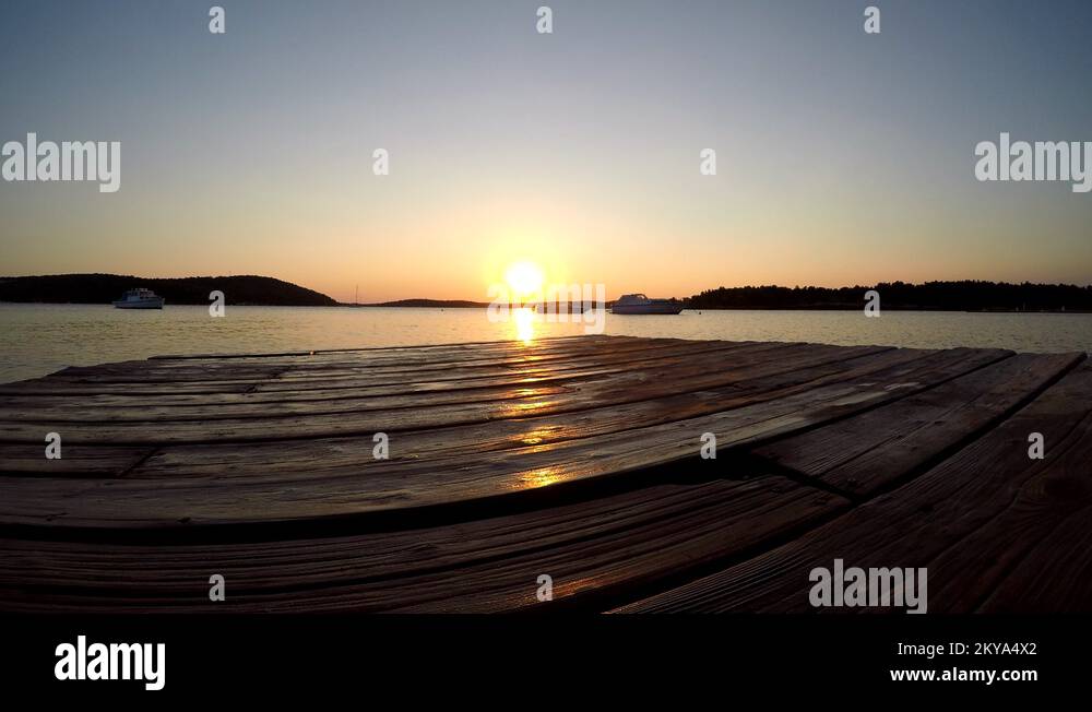 Brother and sister jumping from a pier into the water at sunset SLO MO ...