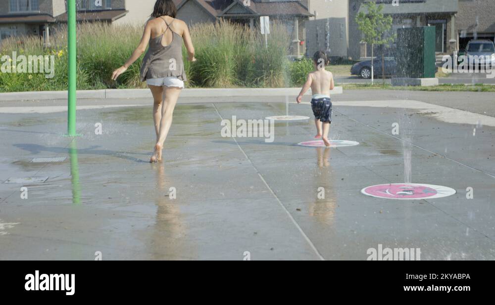 Toddler boy and mother running through water splash pad Stock Video ...