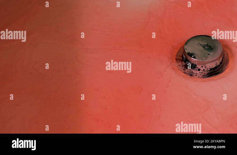 Red blood being washed down a white bathtub drain. Horror movie concept ...
