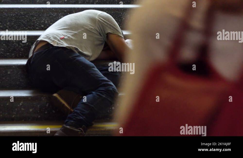 A homeless person sleeps on a staircase in a public area - people ...