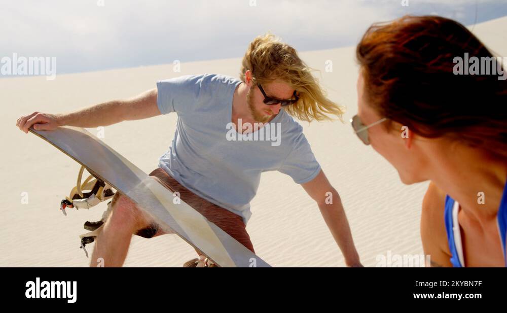 Man rubbing sand over the sand board while woman watching 4k Stock ...
