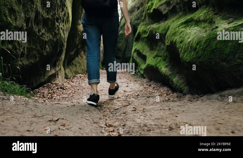 legs of a woman in jeans and crossover, walking alone on a mountain ...