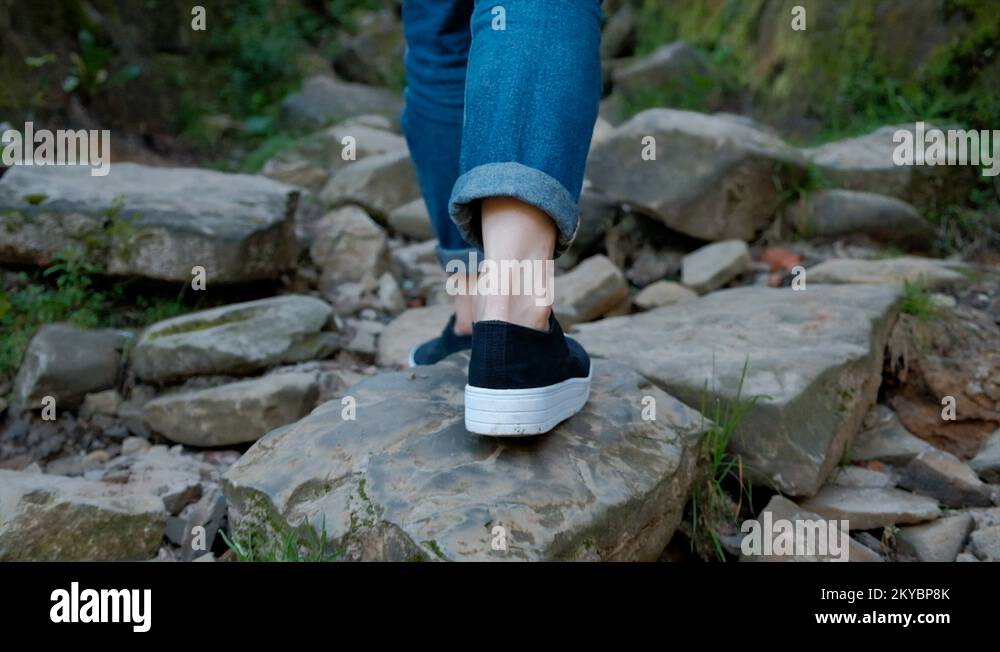 legs of a woman in jeans and crossover, walking alone on a mountain ...