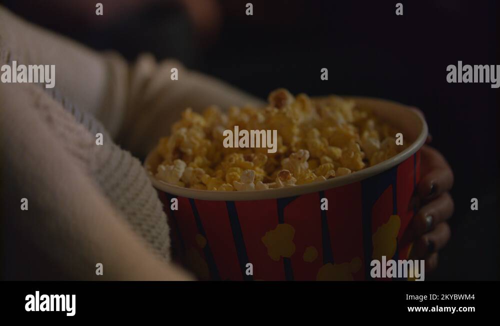 Female hand taking popcorn from paper container. Eating pop corn at ...