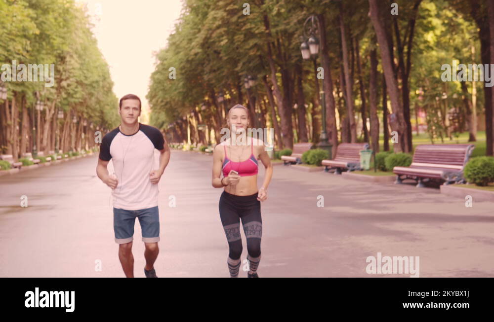 Beautiful young girl and men training runs in the Park, slow motion ...
