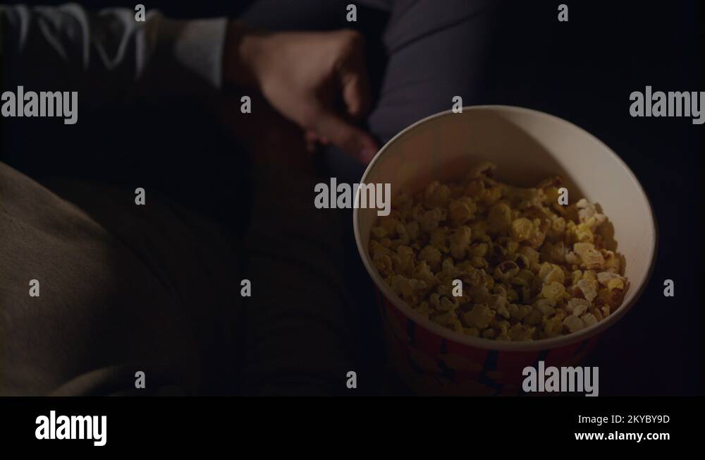 Female and male hand take popcorn grains from popcorn box in slow ...