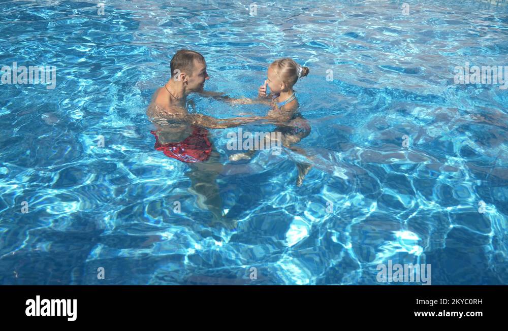 The young father is teaching his little daughter to swim in the pool ...