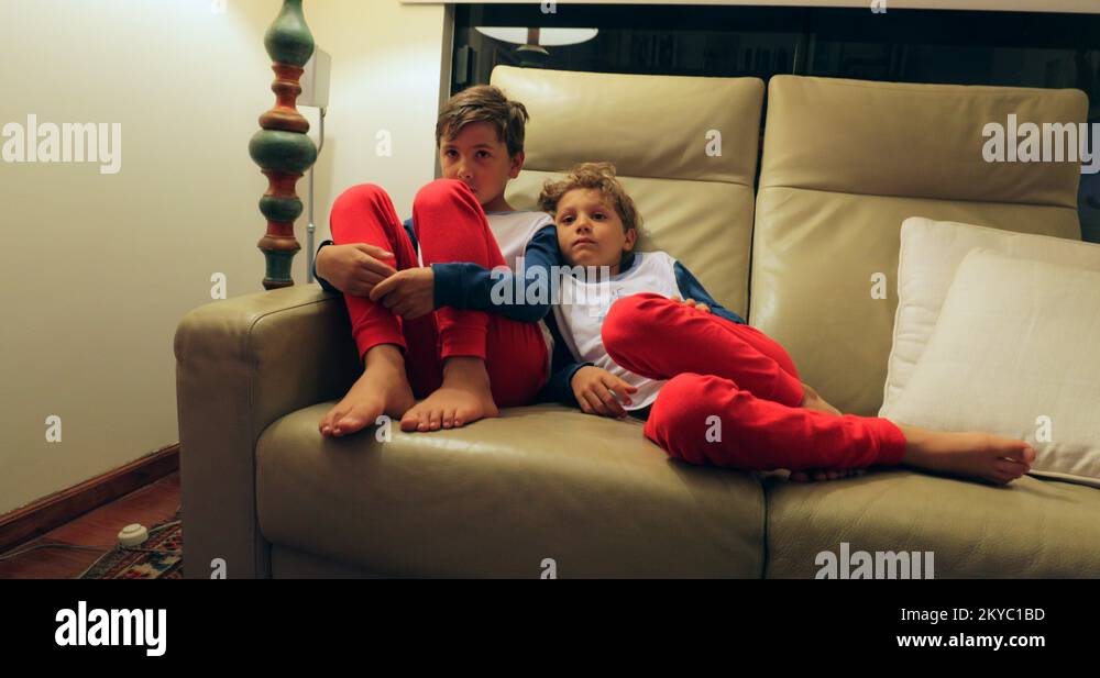 Boys seated on sofa watching TV off camera. 4K candid clip of children ...
