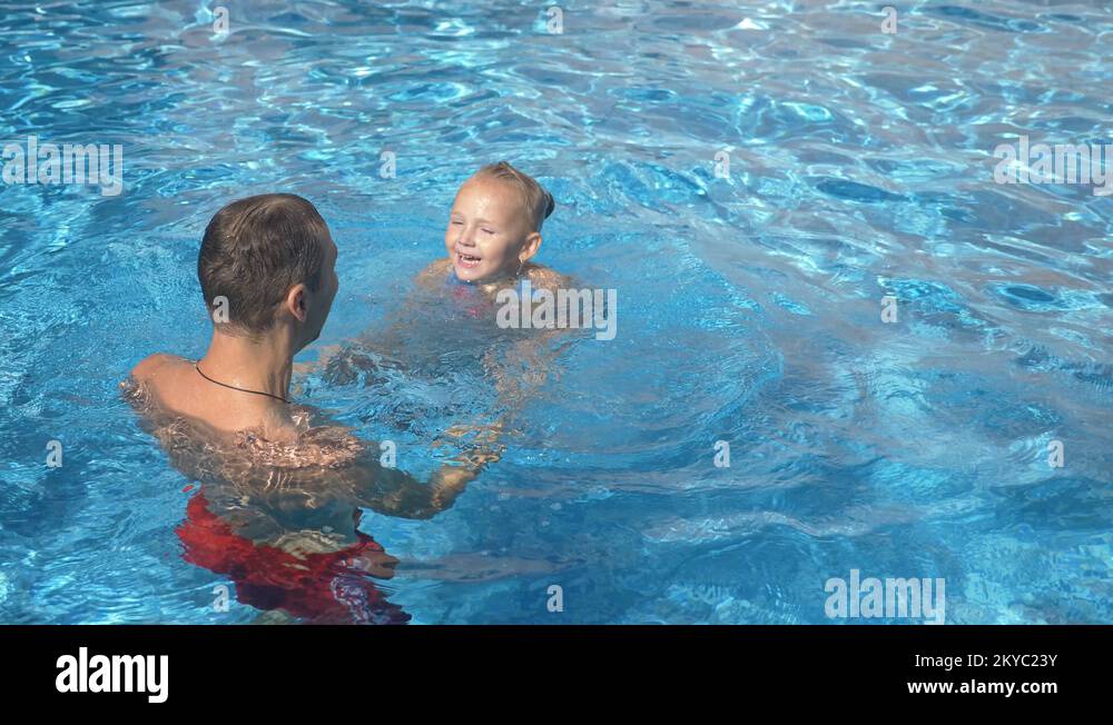 The young father is teaching his little daughter to swim in the pool ...