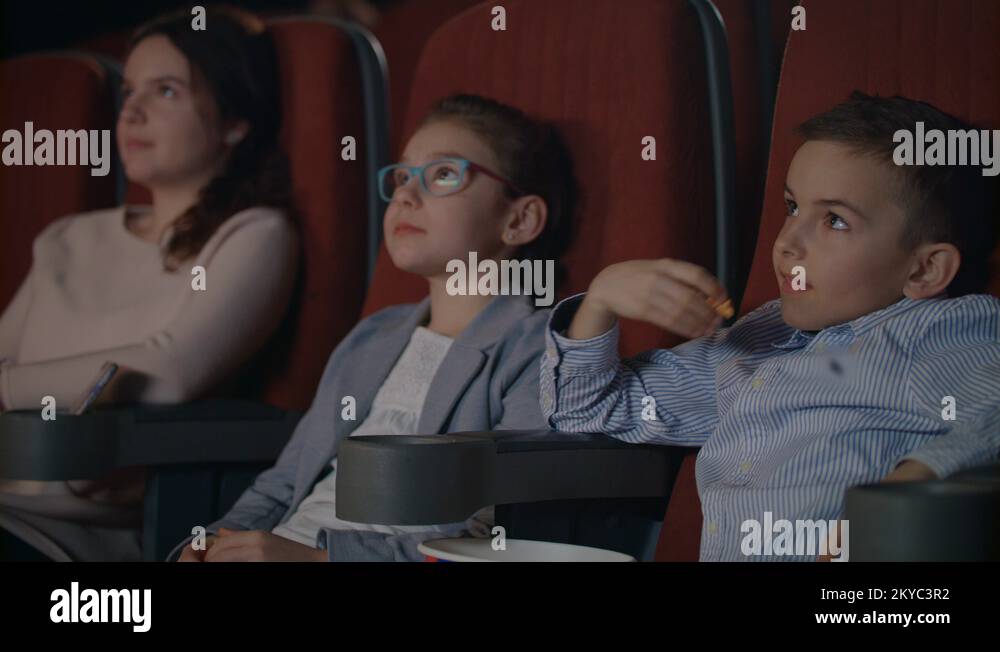 Kids are frightened at movie theatre. Scared children cover faces by ...