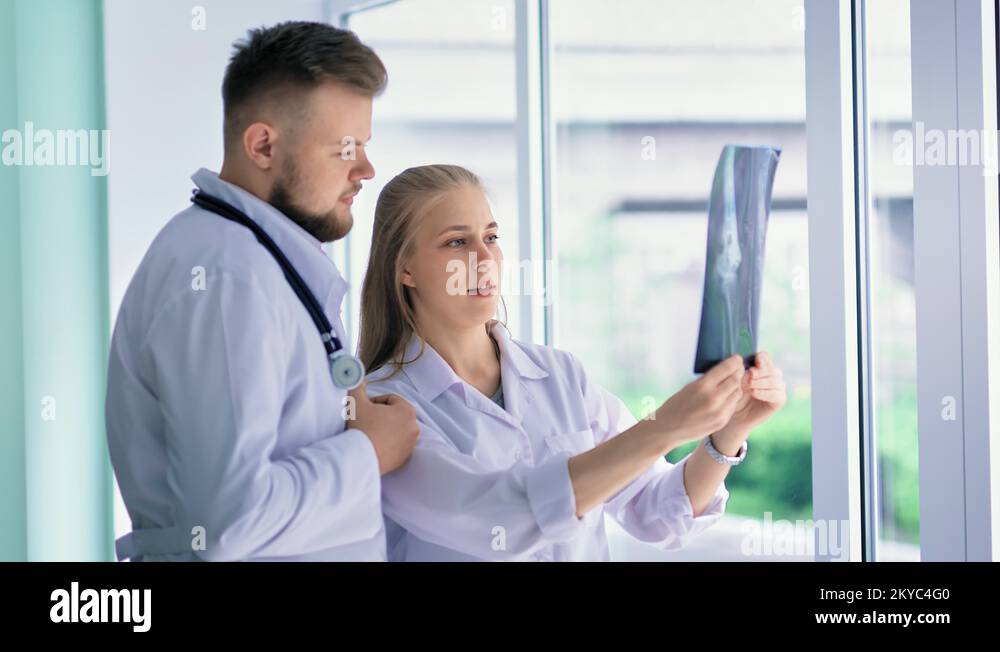 Female and male doctor in white coat reviewing x-ray pointing on ...
