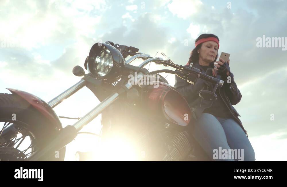 Biker old woman in leather jacket and gloves sitting on his cool ...