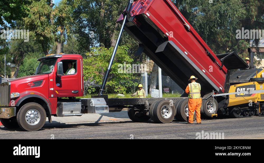 Truck loads asphalt into paver machine during road repair, Los Angeles ...