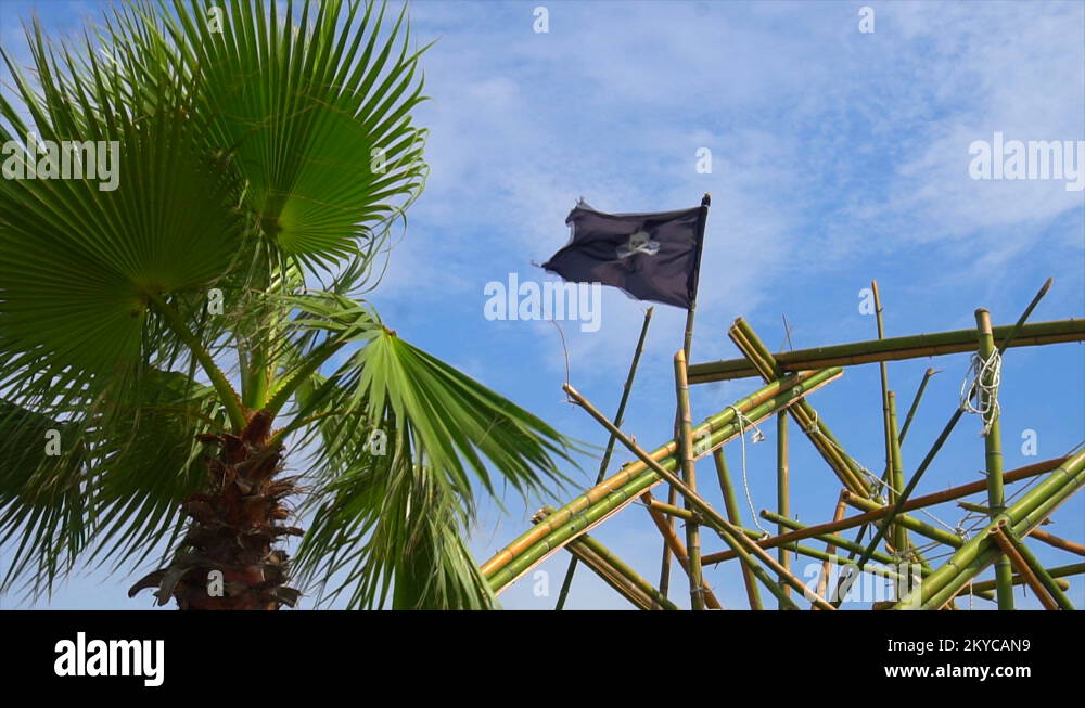 Torn tattered pirate flag waves in the wind tied to rigging on tall ...