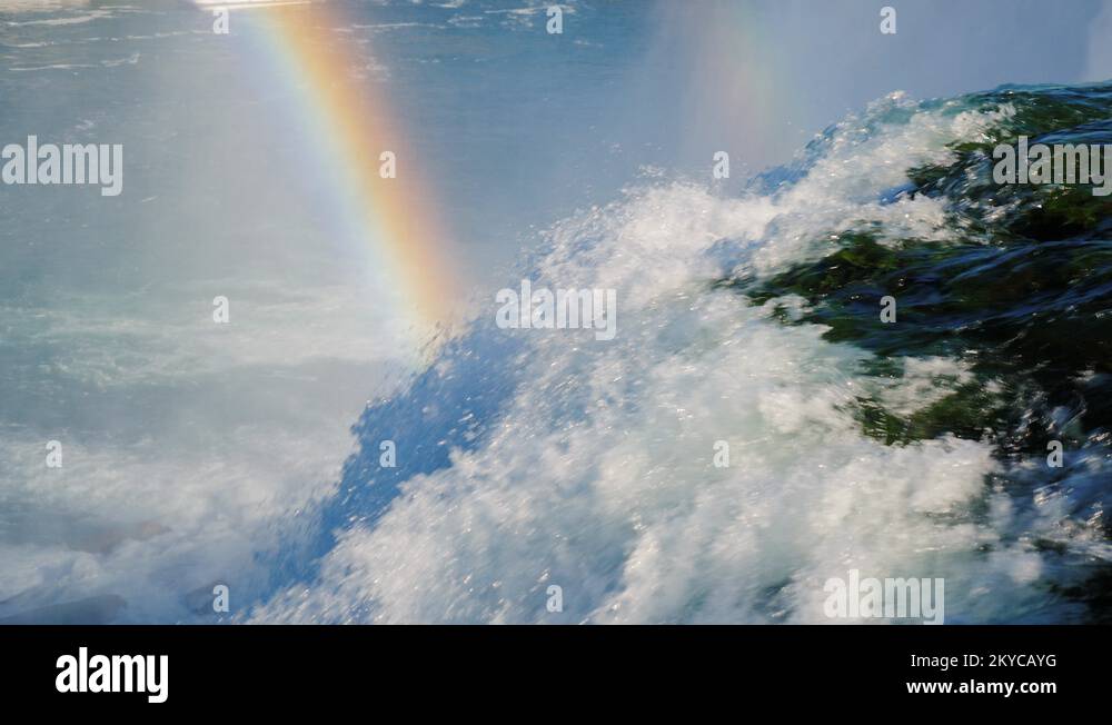 Niagara Falls. Streams of water rush down foaming. Large rainbow over ...