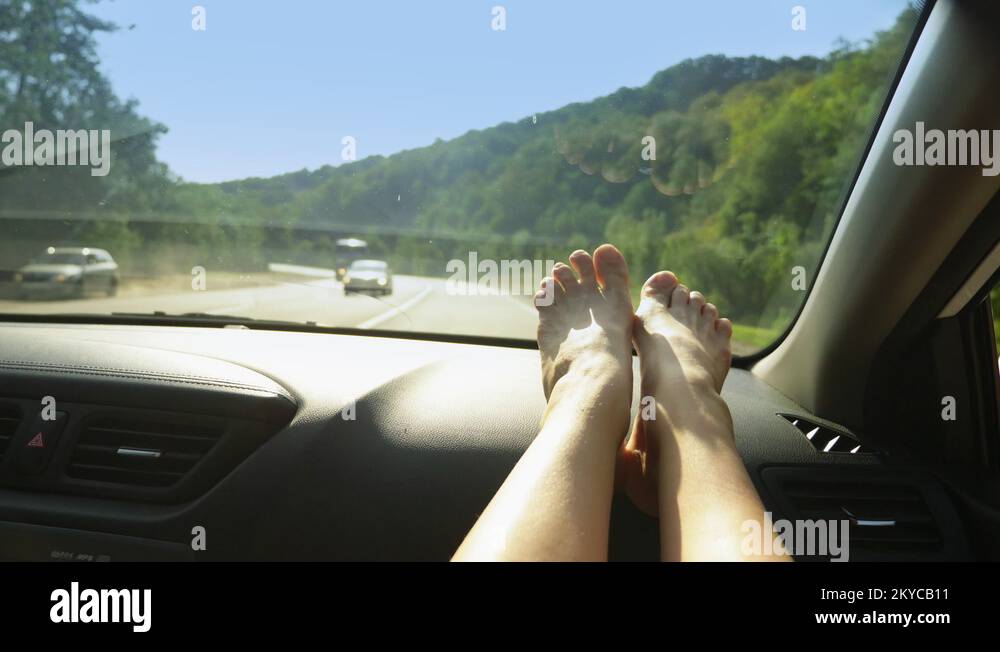 female feet on the dashboard of the car, from the side of the passenger ...