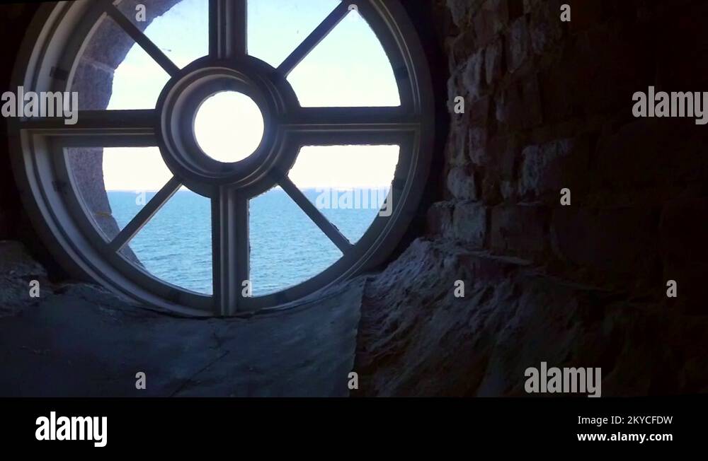 Pan view of endless sea, from a round window, inside a huge lighthouse ...