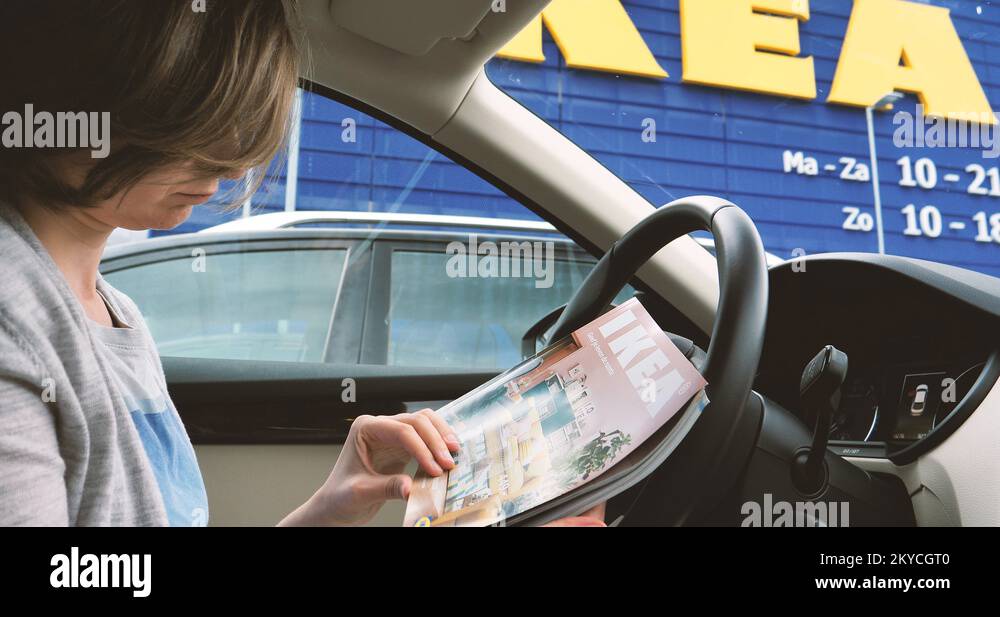 Woman in car reading IKEA magazine catalog in front of store Stock ...