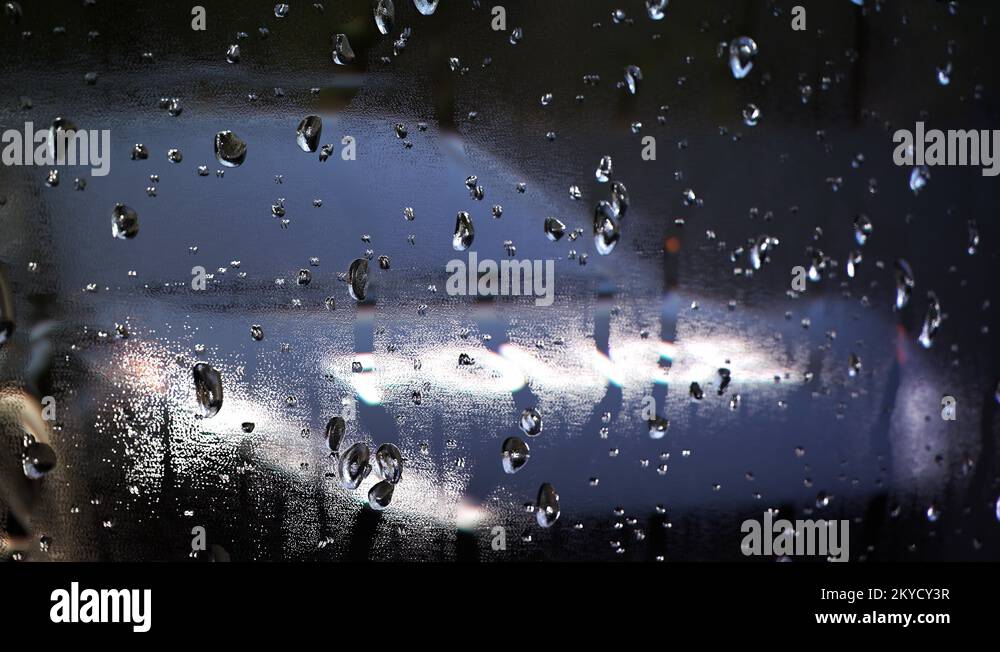 "Police car lights flashing through a window with water droplets and ...