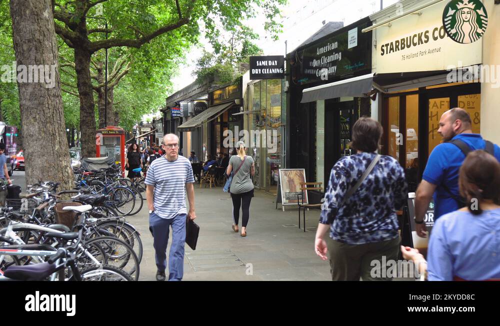 People walking down sidewalk of quiet shopping street in suburb of ...