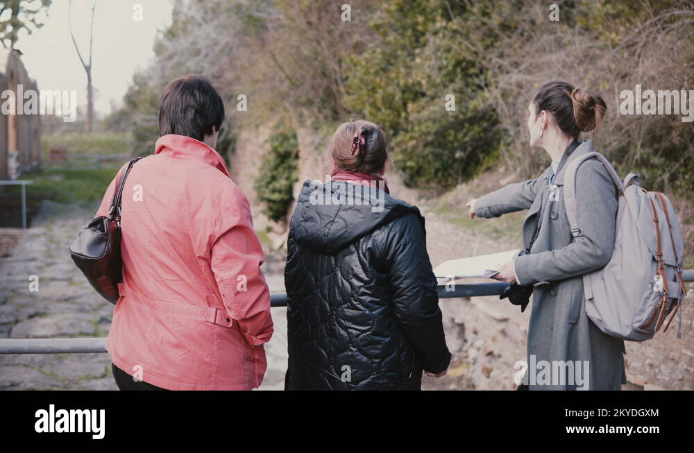Young beautiful European female tour guide giving a walking tour to two ...