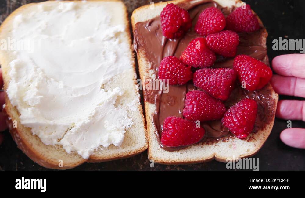 Cutting a raspberry, chocolate and cream cheese sandwich in half Stock ...