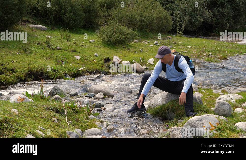 Tourist man washing hands and face by clear water from flowing river in ...