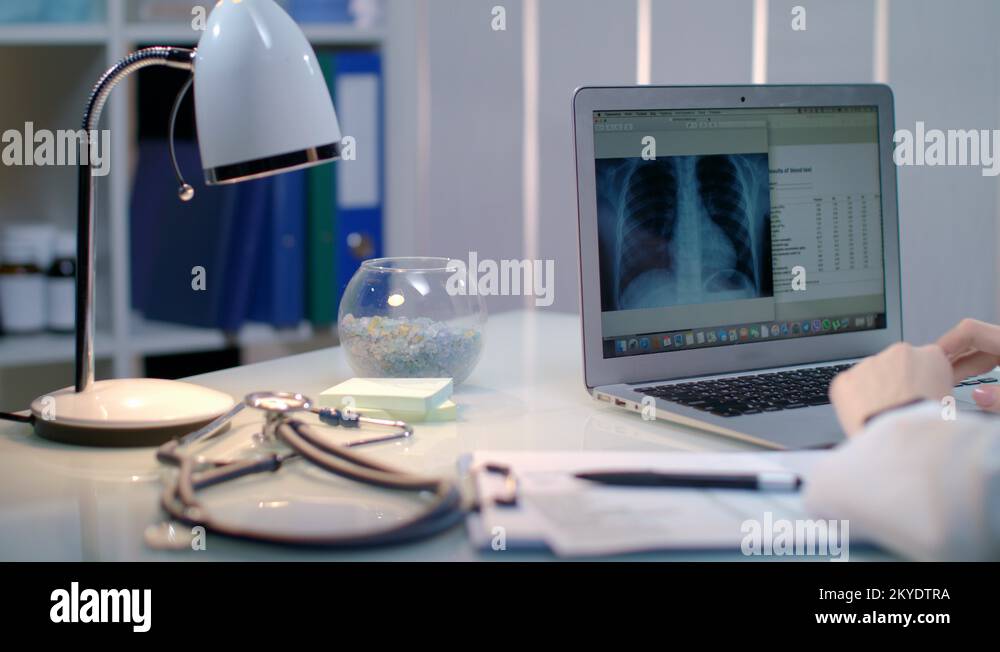 Doctor working with xray on laptop at workplace. Radiologist check x ...