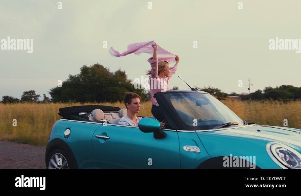 4K side view of a happy young couple out in the country driving in a ...