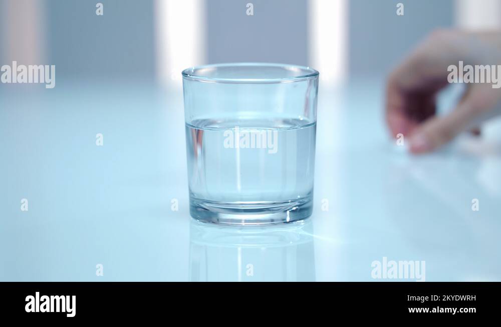 Fizzy tablet dissolving in water glass. Effervescent tablet in glass ...