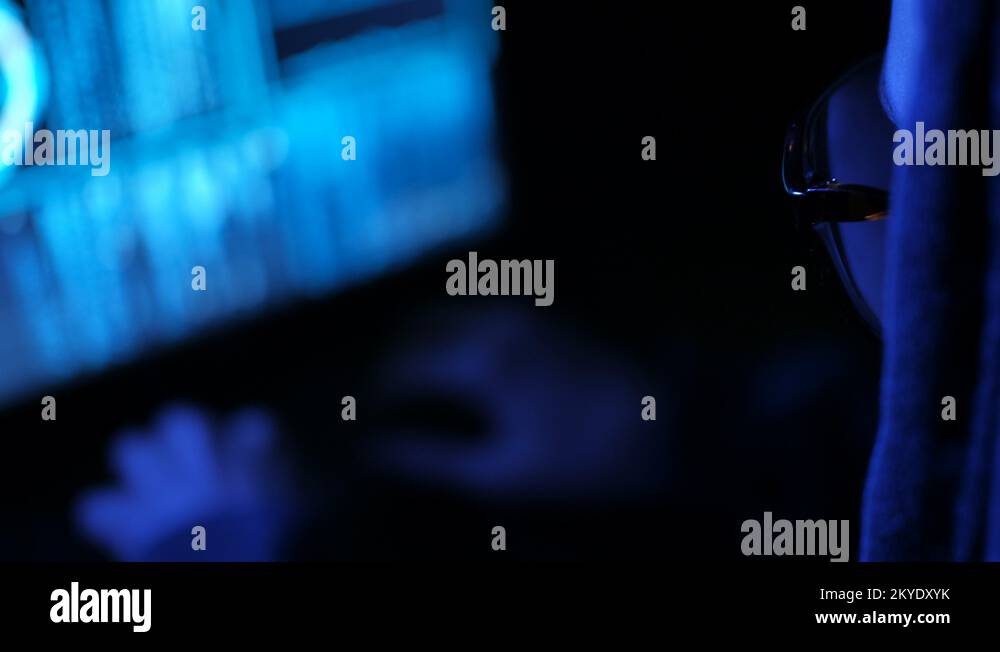 Young cyberpunk student hacker typing on the computed under the blue ...