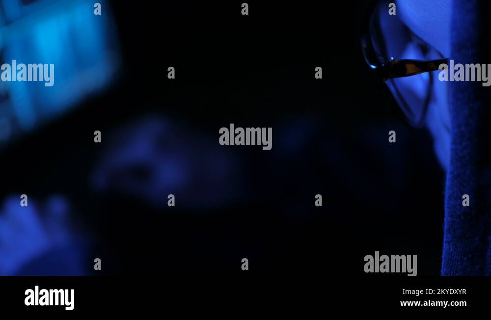 Young cyberpunk student hacker typing on the computed under the blue ...