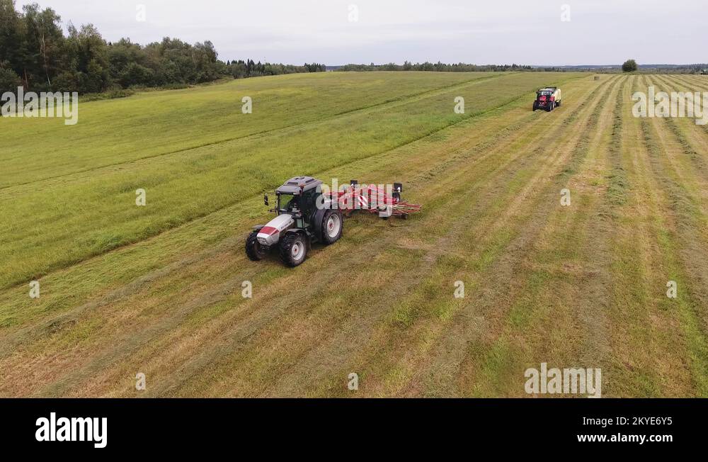 Drone camera view of big grey tractor moving with working red round ...