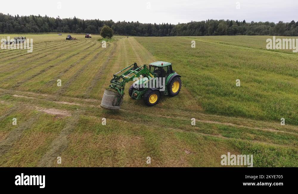 Drone camera shows big green tractor bale elevator carries round shaped ...