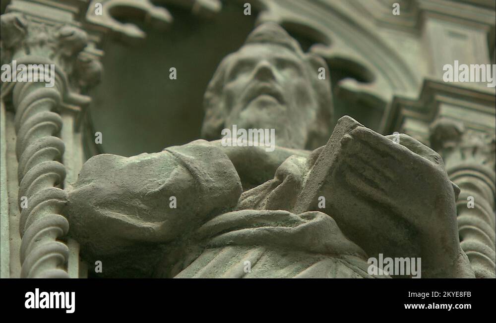 Stone statue of man holding book seen from below at The Basilica di ...