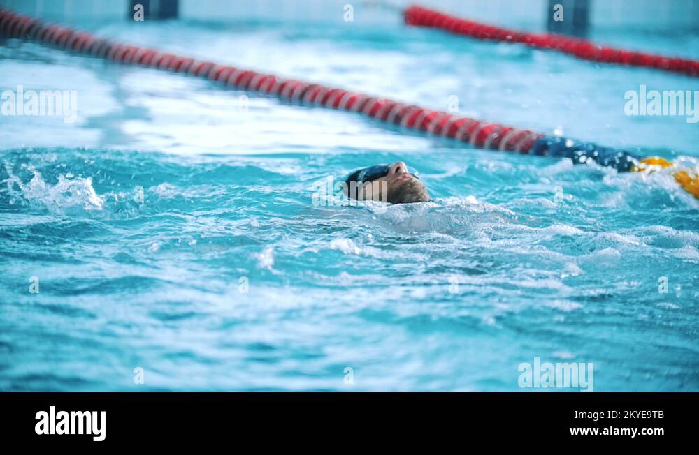 Disabled man swims on the back in a swimming pool. Slow motion. The ...