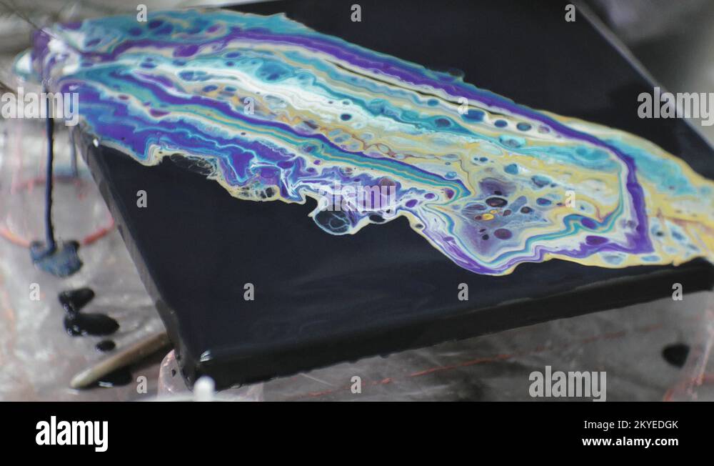 women in an art studio mix paints and draw on canvas in fluid art ...