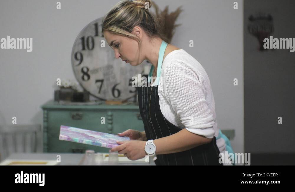 women in an art studio mix paints and draw on canvas in fluid art ...