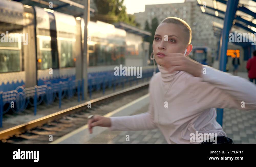 unusual dance of young bald caucasian girl on platform with train ...