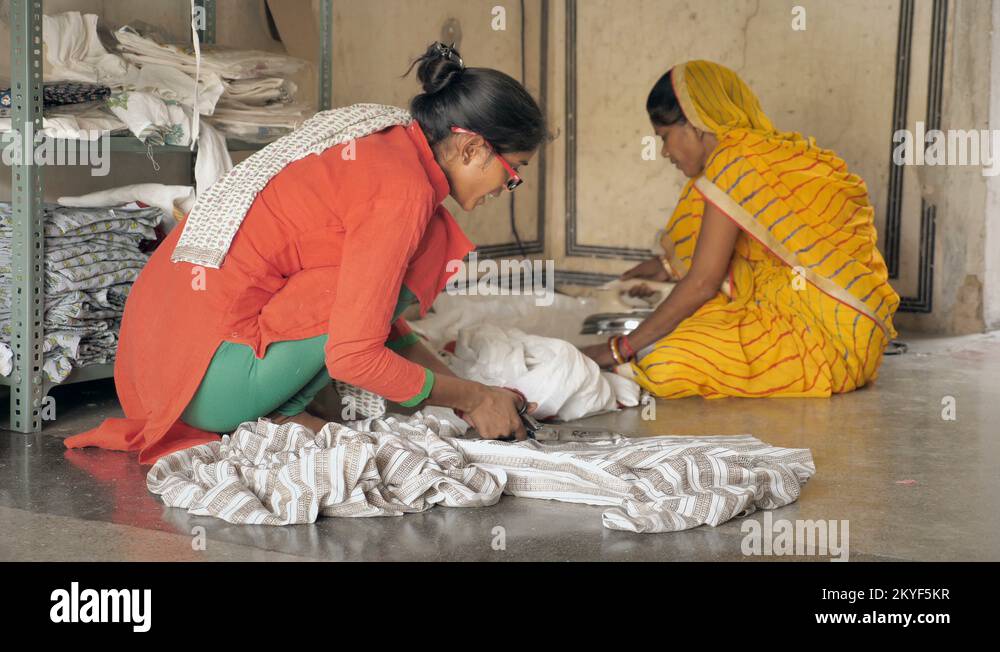 Two female coworkers in a traditional attire working in a garment ...