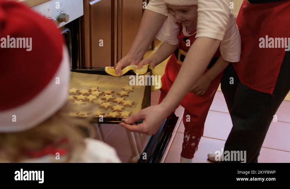 Mother and two small children are about to take cookies from the stove ...
